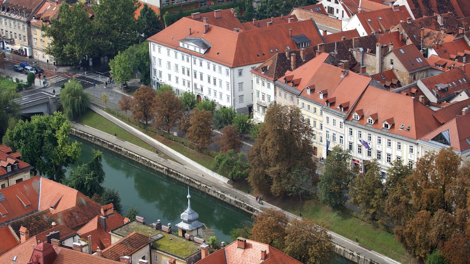 Castelo de Liubliana caracterizando uma cidade, um rio ou córrego e um pequeno castelo ou palácio