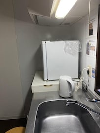 Mini fridge sat on a wooden platform to cover an inoperative gas range. Toaster was also inoperative. No microwave included.