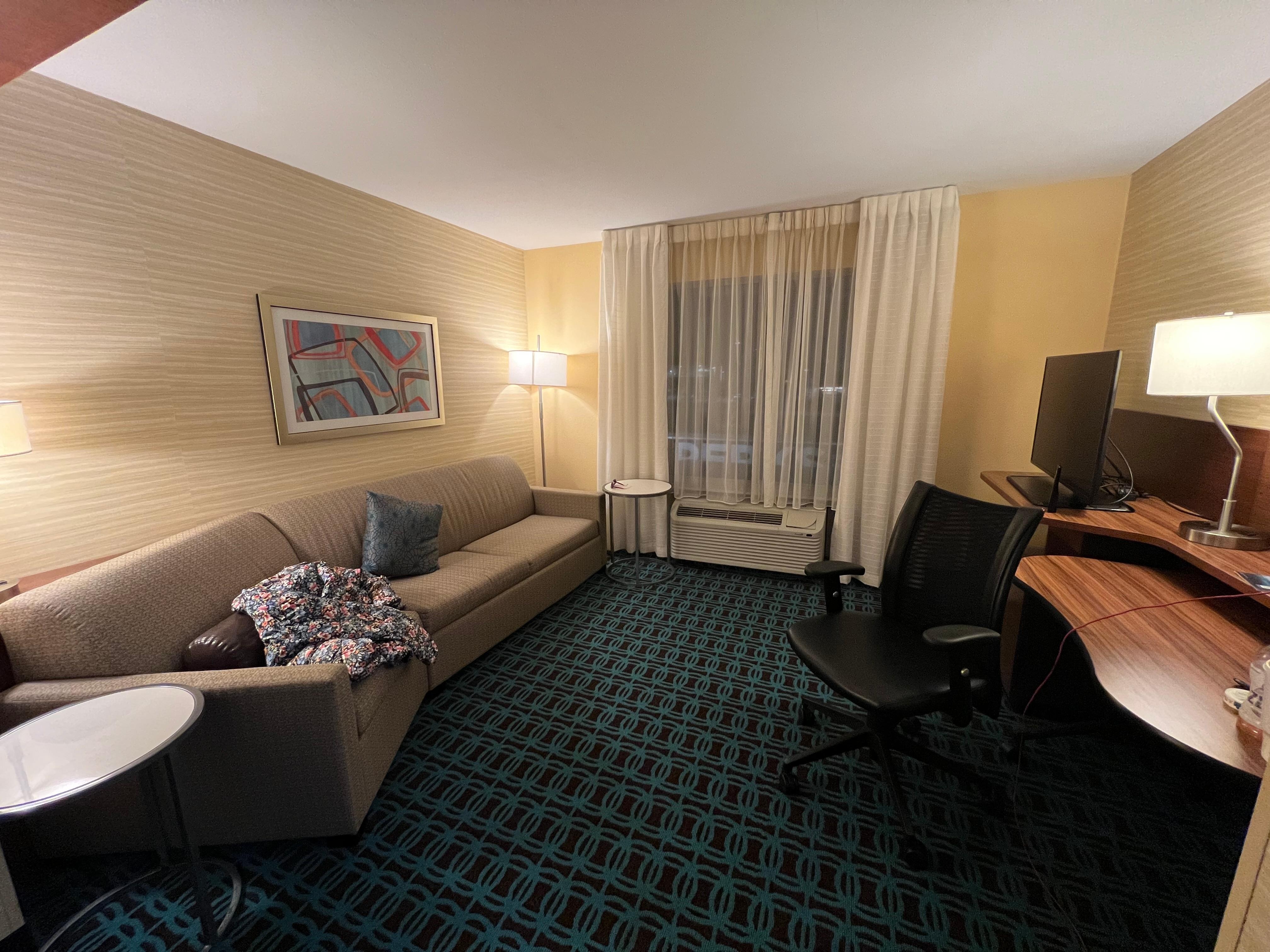 Living area with TV, sofa, 2 end tables, and desk area