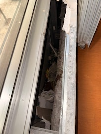 Buraco com entulho e lixo entre a janela e o aquecedor