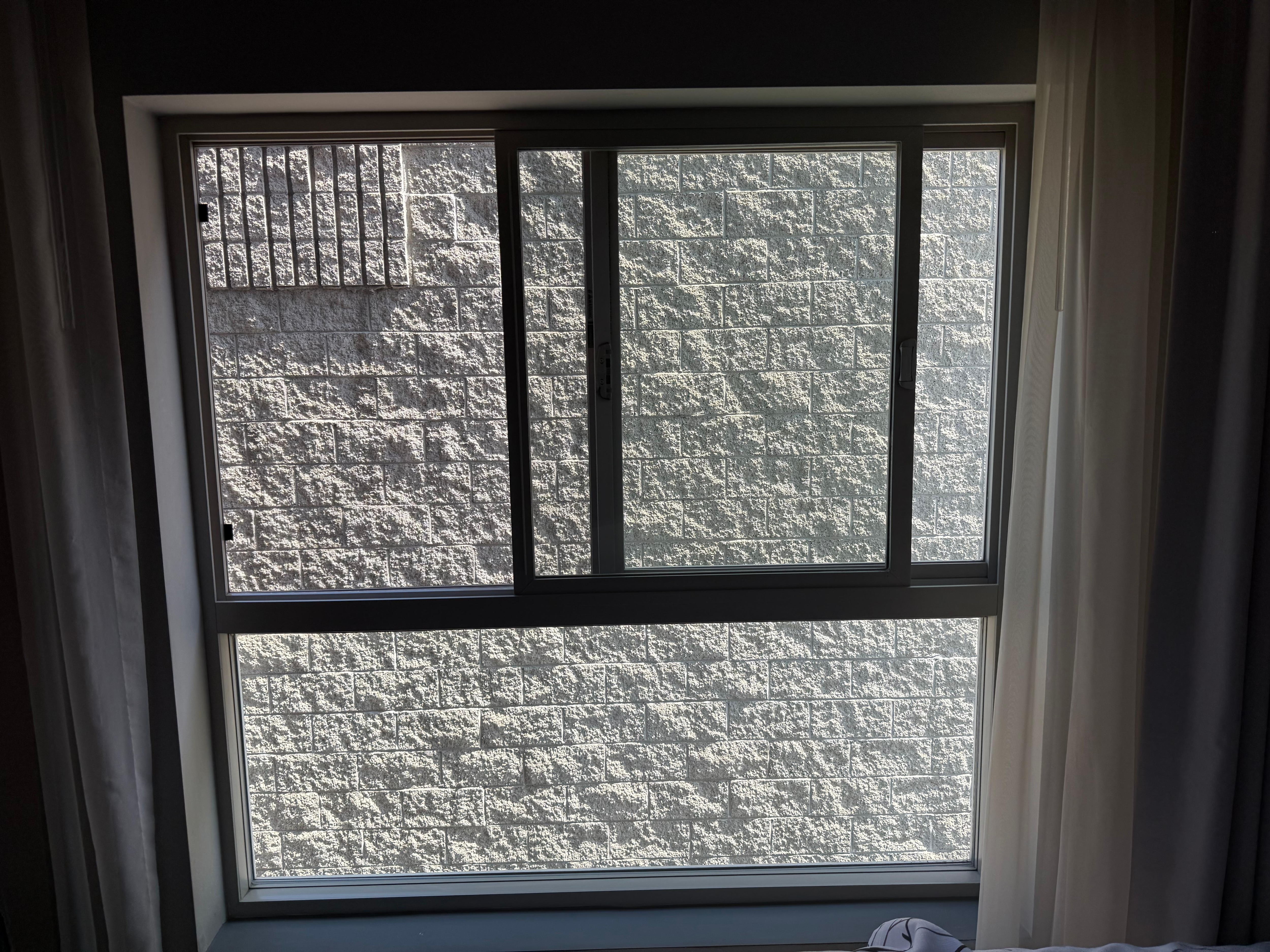 A gray wall view from the only window 