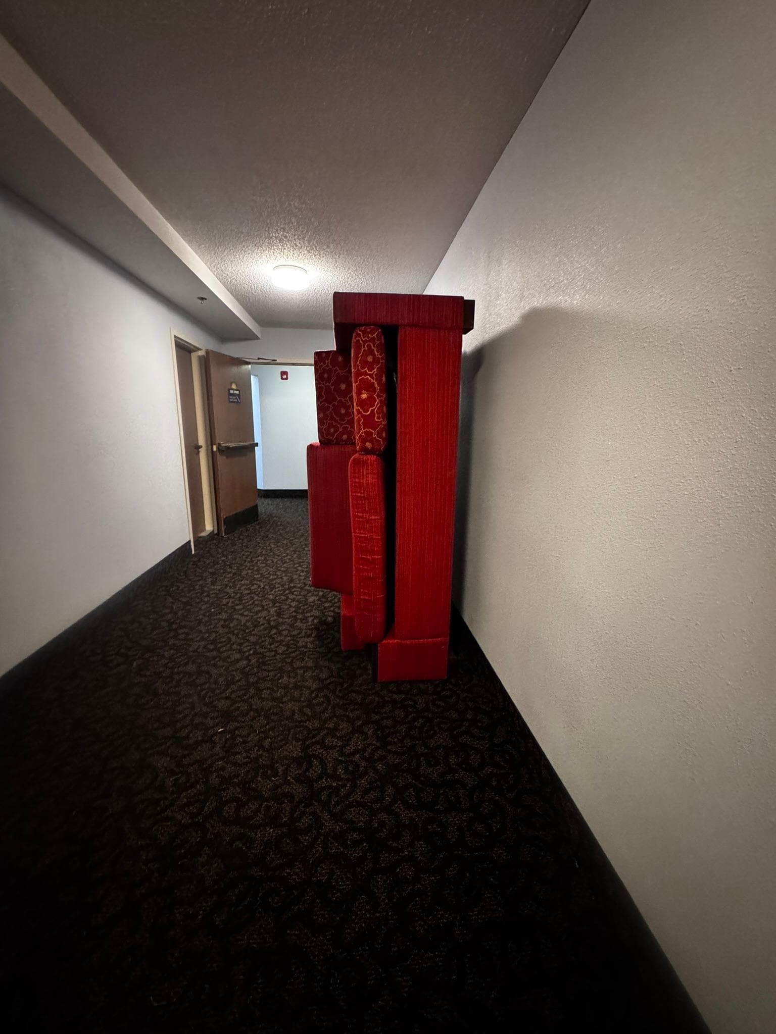 Furniture stored on its side in guest hallway near room entrance creating an obstruction and potential safety concern