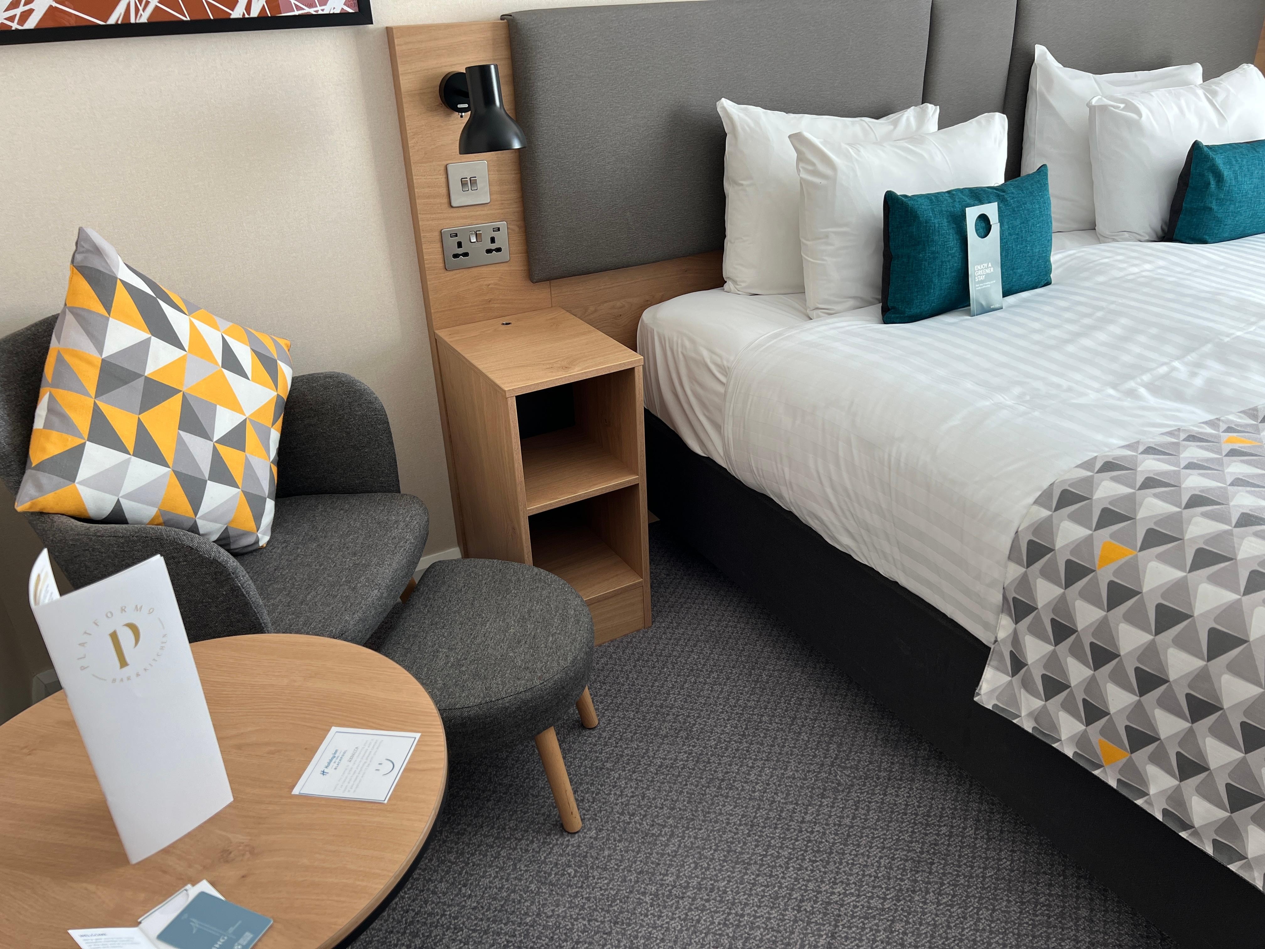 Comfortable bed and nice chair with footstool.