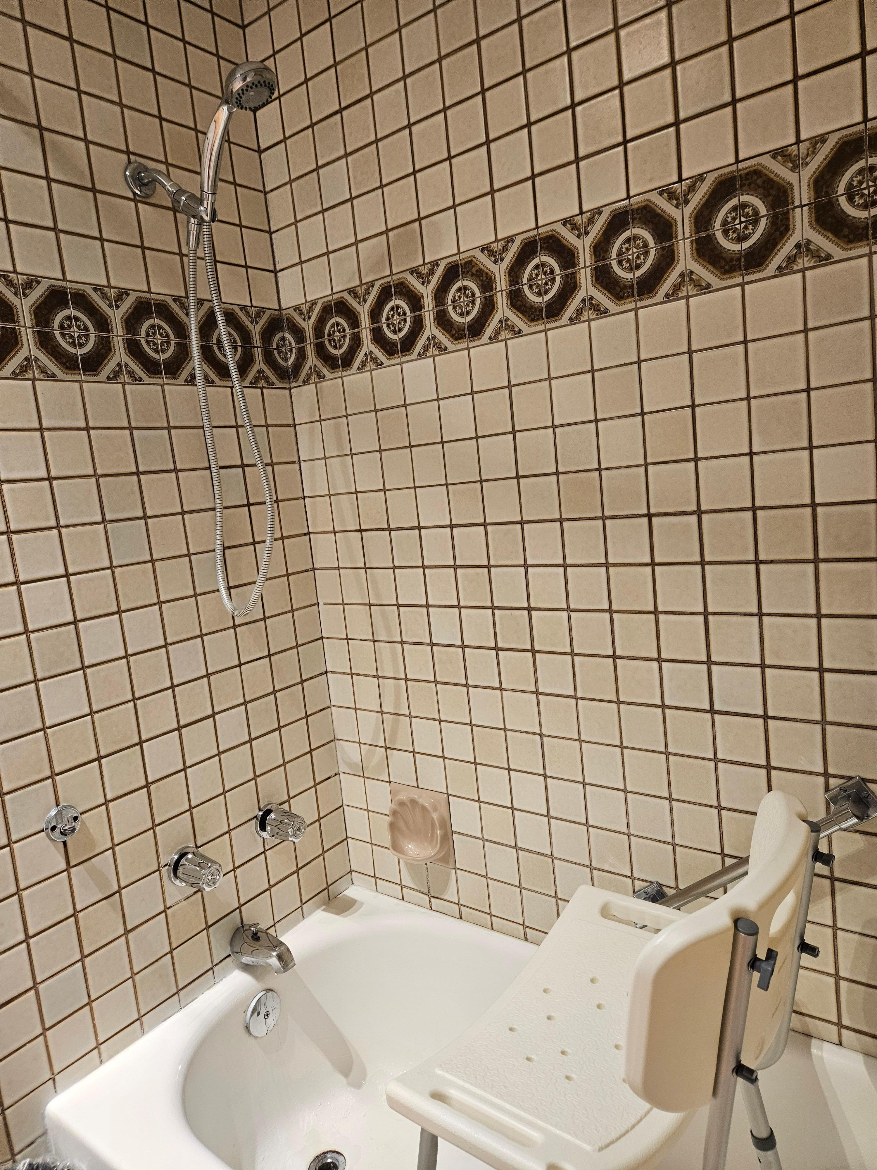 Shower nozzle not reachable by handicap person sitting in Shower. No hand rails at front of Shower to assist amputee  into Shower chair