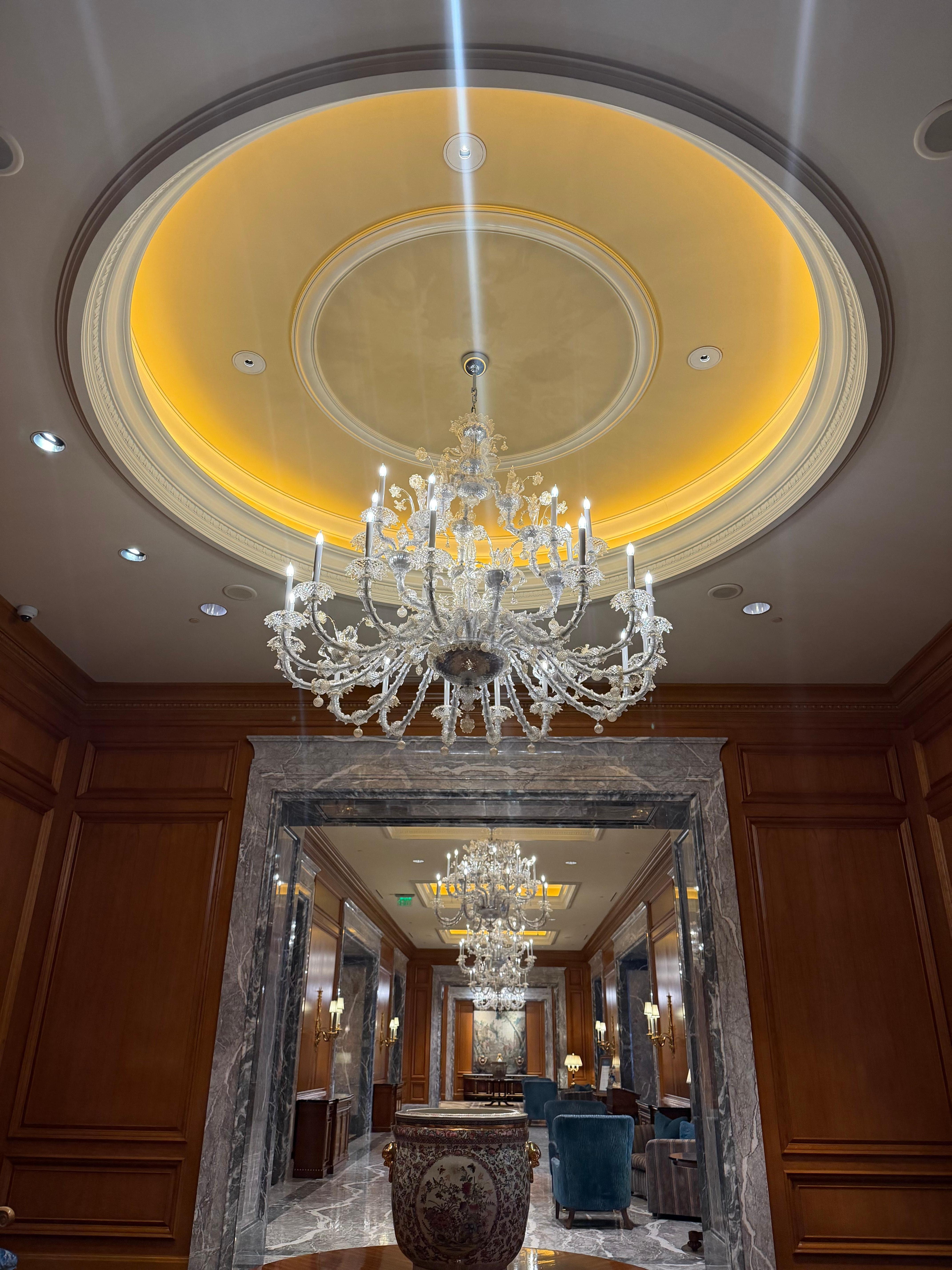 Main hallway with lots of marble and chandeliers. 