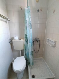 Salle de bain très exiguë, avec un volumineux robinet de baignoire dans la douche