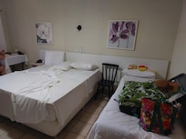 Cama de casal e de solteiro com uma mesinha com 2 cadeiras no canto.