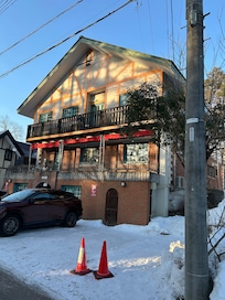 View from the street. The warm room entrance is in front on the lowest floor. The main entrance is on the far side on the second level.