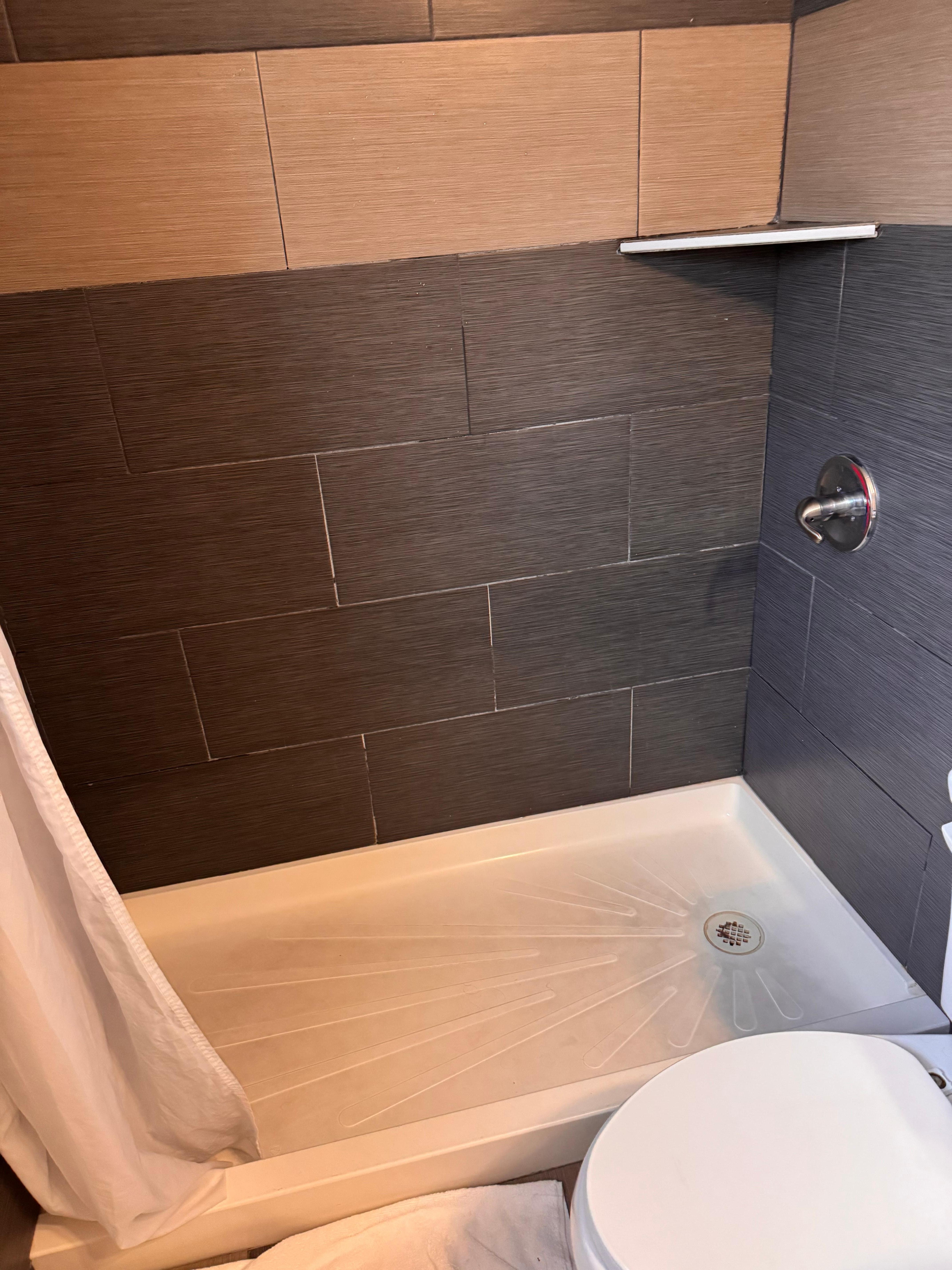 Nasty cramped shower, used to have curved bars, now just a tension rod.