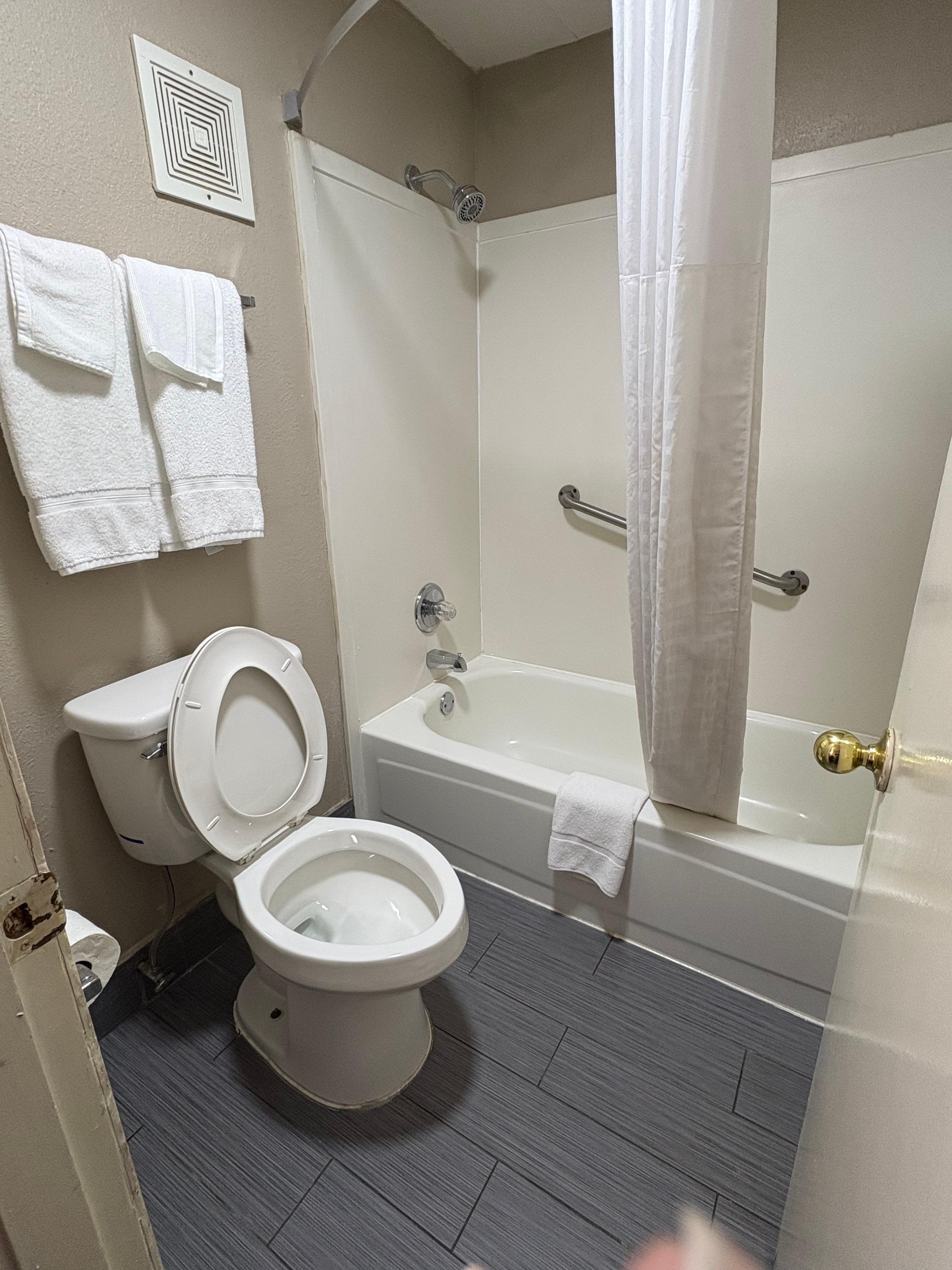 Clean bathroom with vent and grab bar in shower.