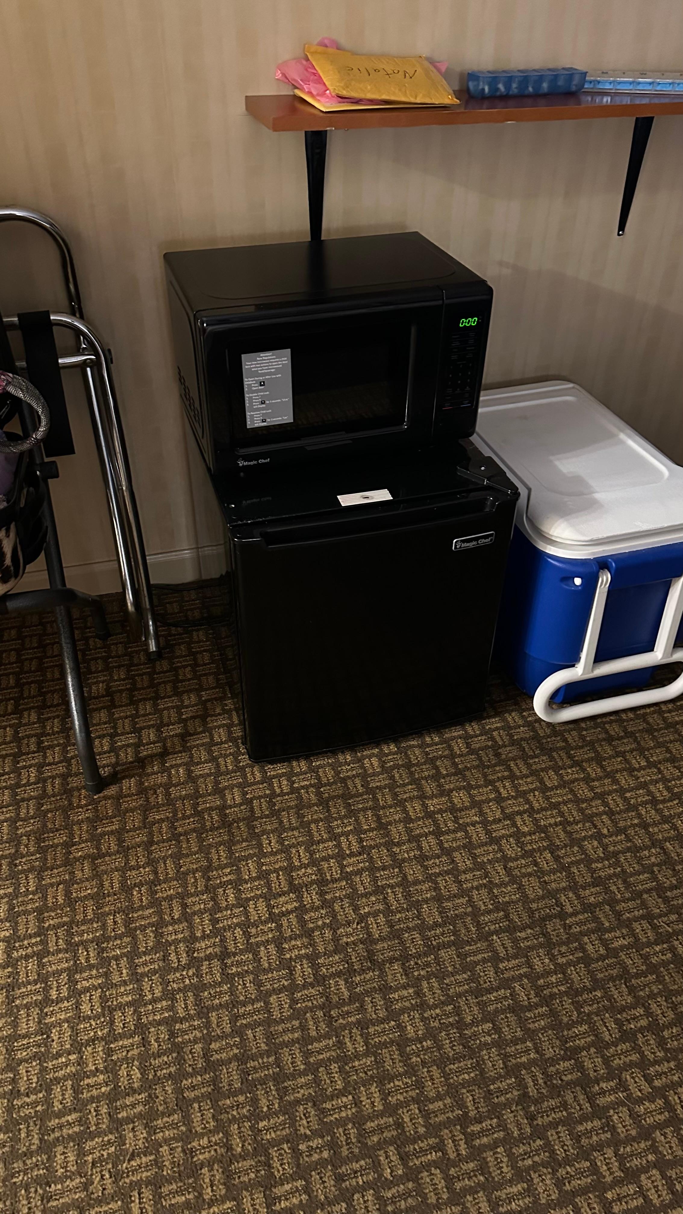 Fridge and microwave sitting on floor. 