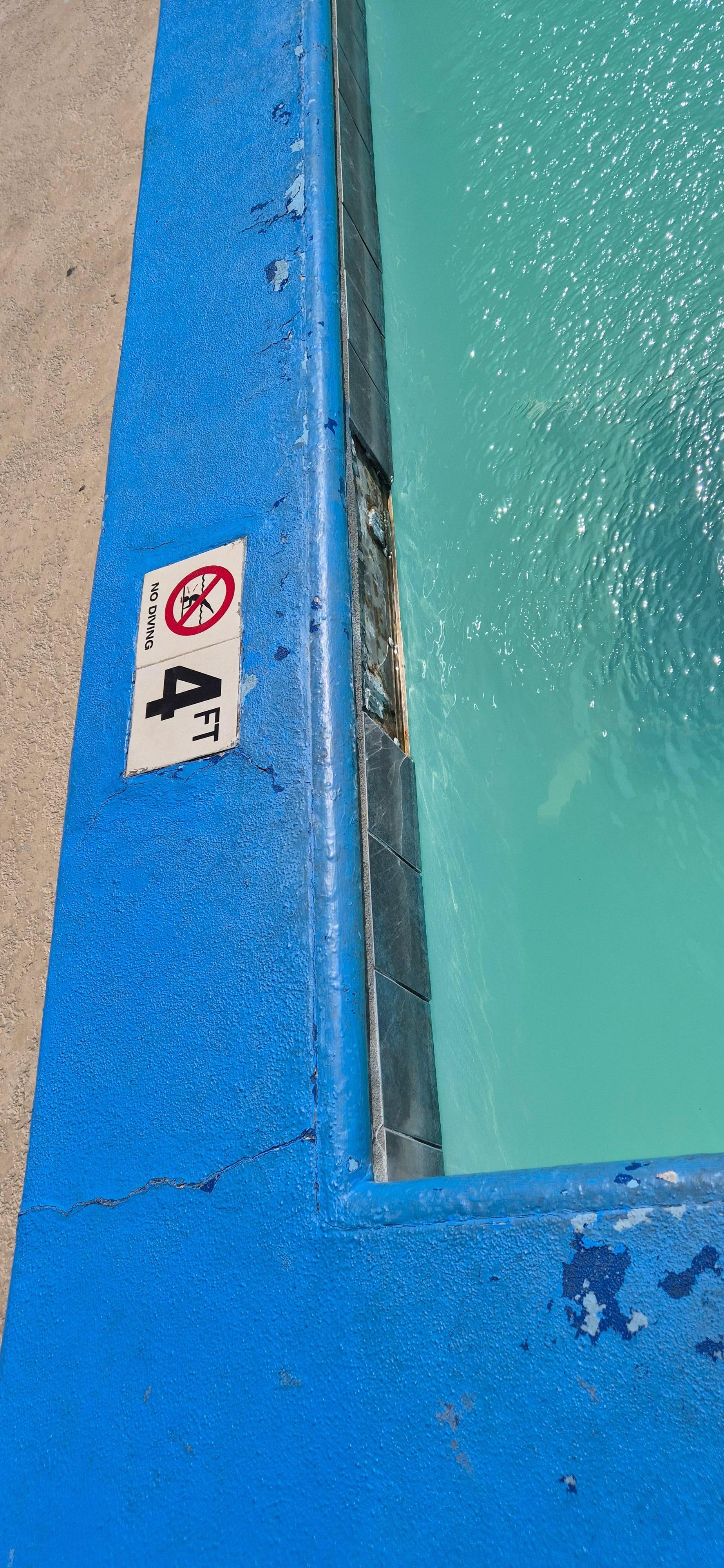 Deck chair at bottom of pool like a dump. 