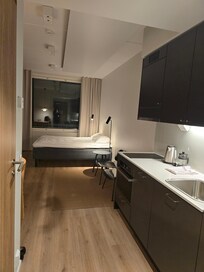 Chegada no quarto, com cozinha à direita e porta do banheiro à esquerda