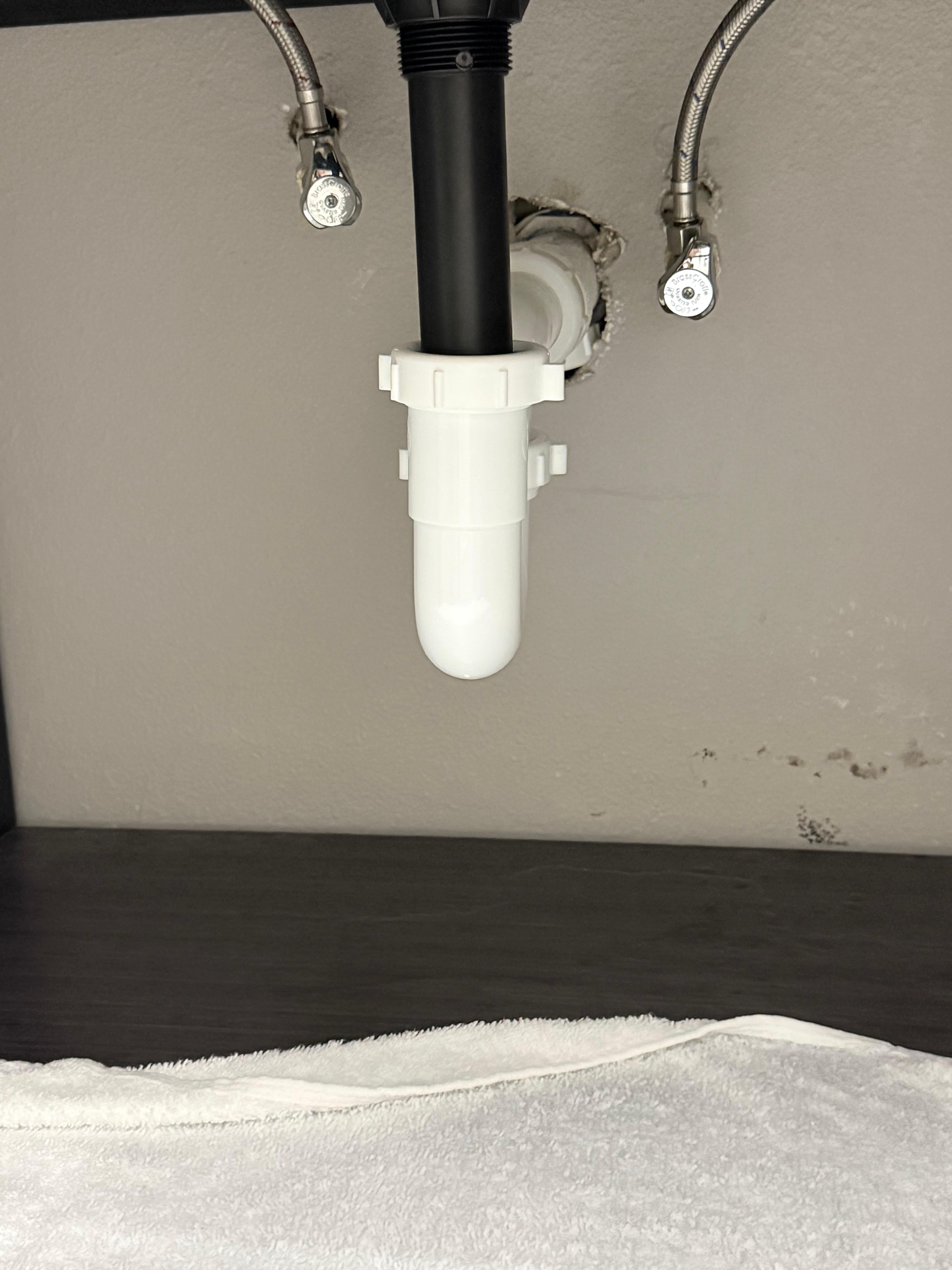 Under bathroom sink, water dripping. 