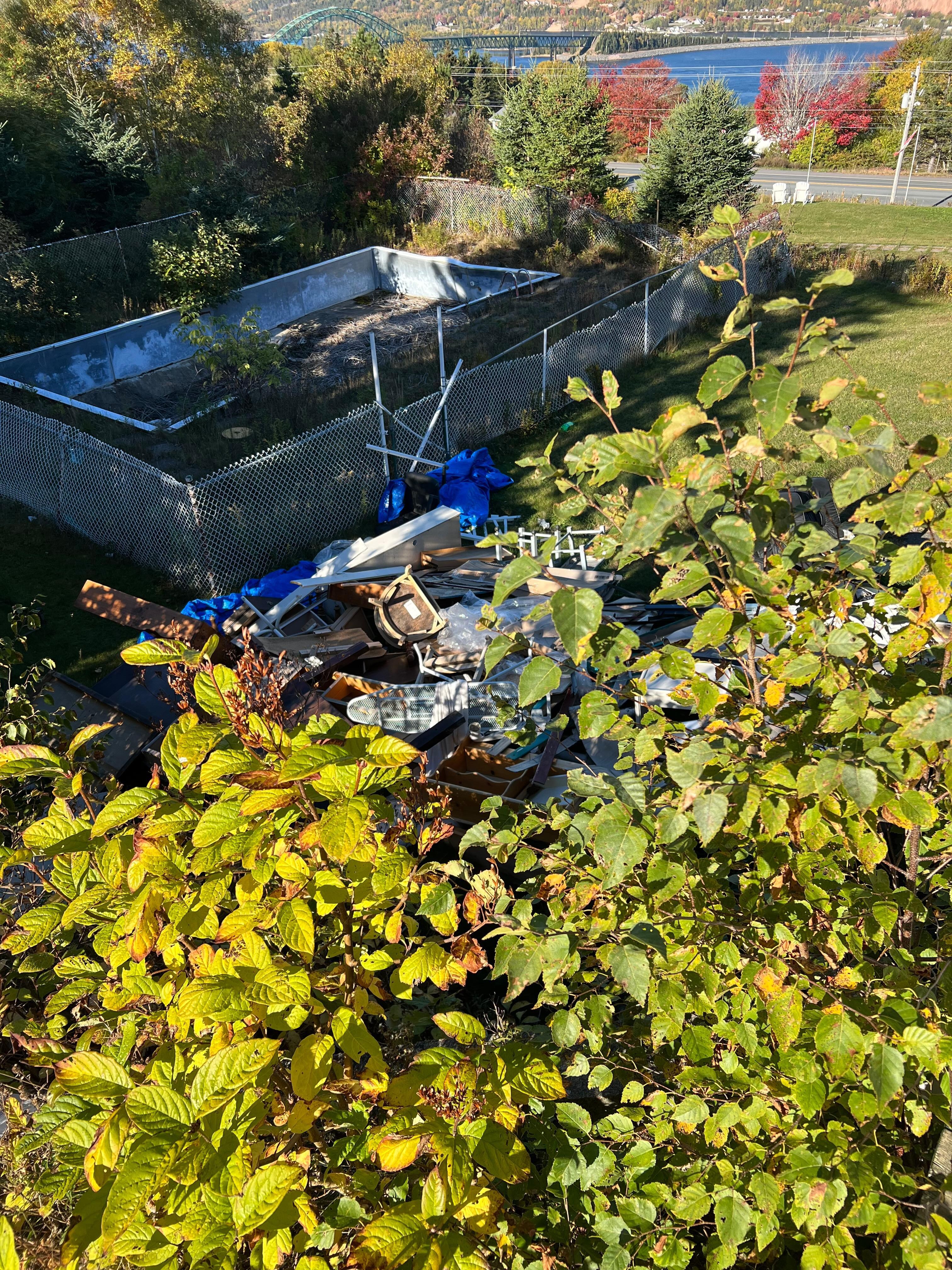 Pile of furniture and appliances dumped outside of room with pool used as a dump 