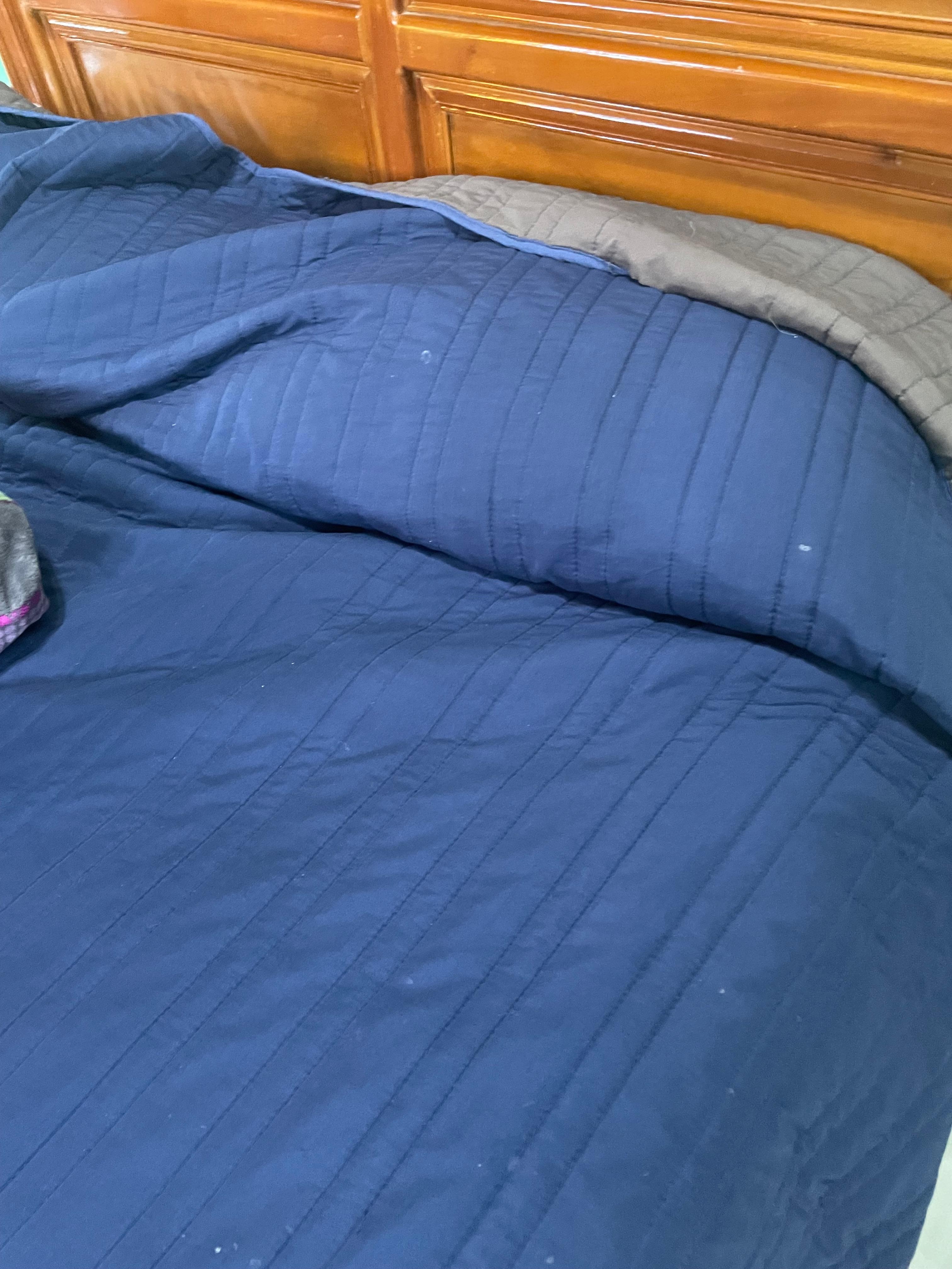 Cama con colcha salpicada con algo y sin extender a la entrega de la habitación. 