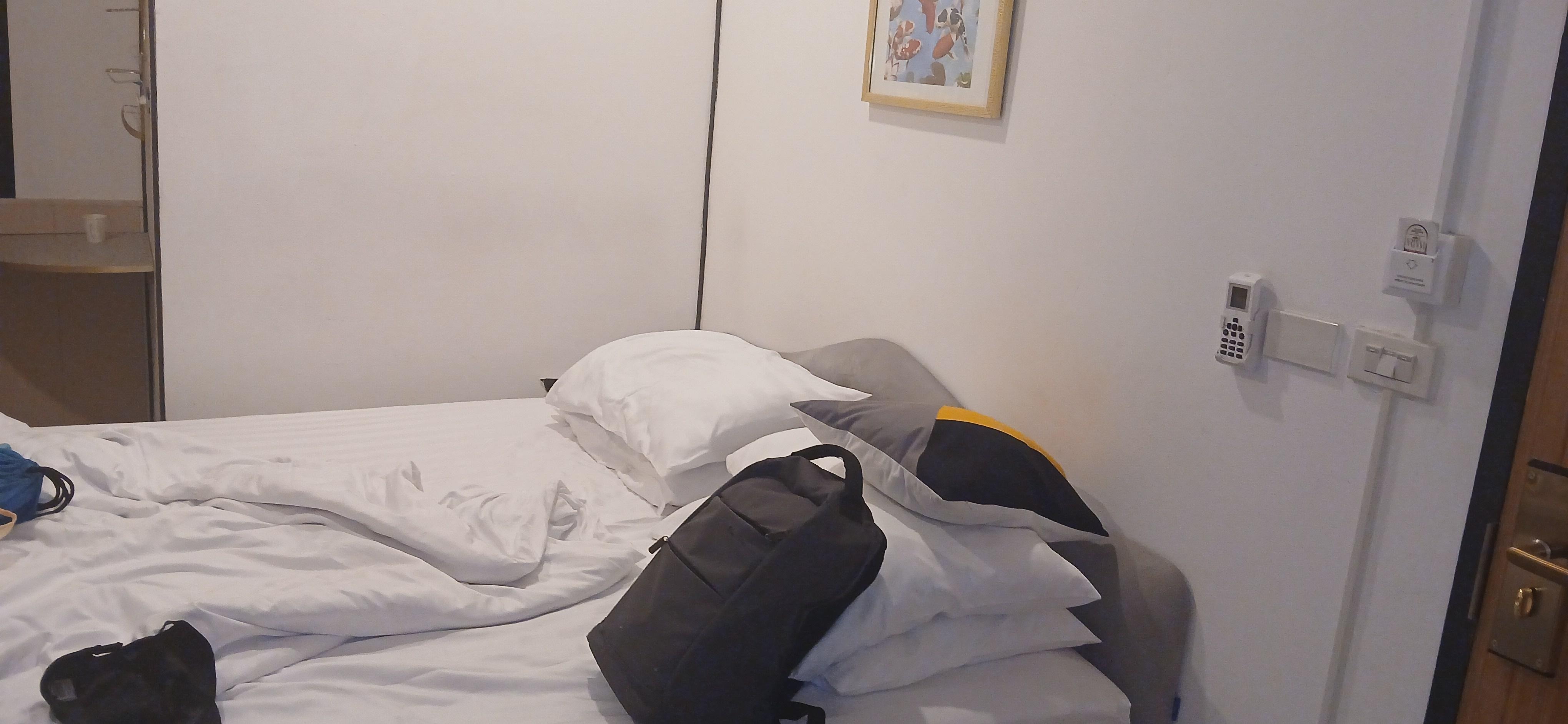 bed pushed into corner,small room no bedside table or lamp
