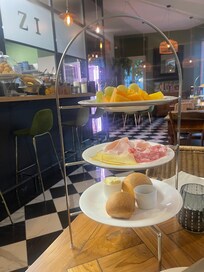 Fick ett fat med bröd, smör o pålägg. Utöver det fanns även croissanter o enklare tårtor samt muffins. De tog beställning på kaffe eller te.