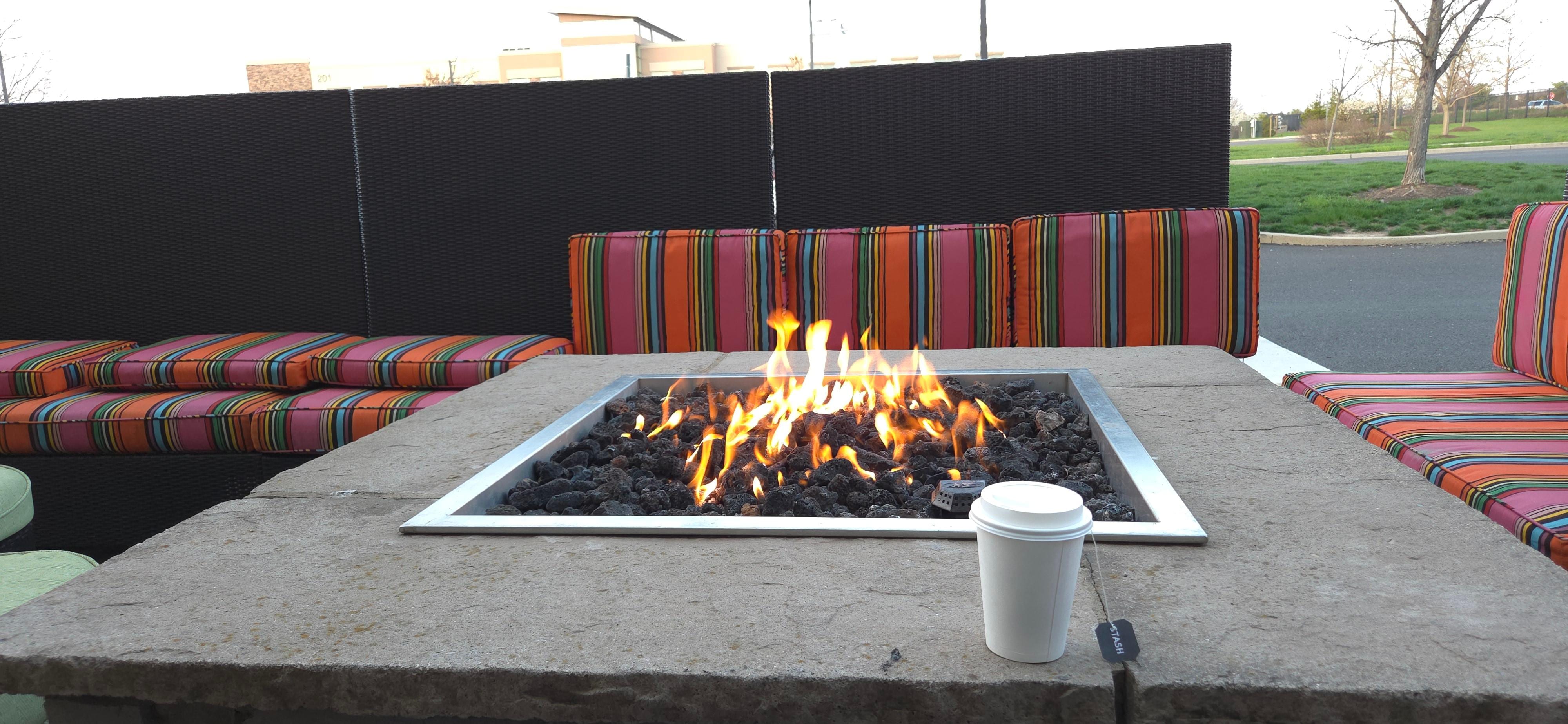 Outdoor gas fire put with decent cushioned seating area, along with tables and chairs. 