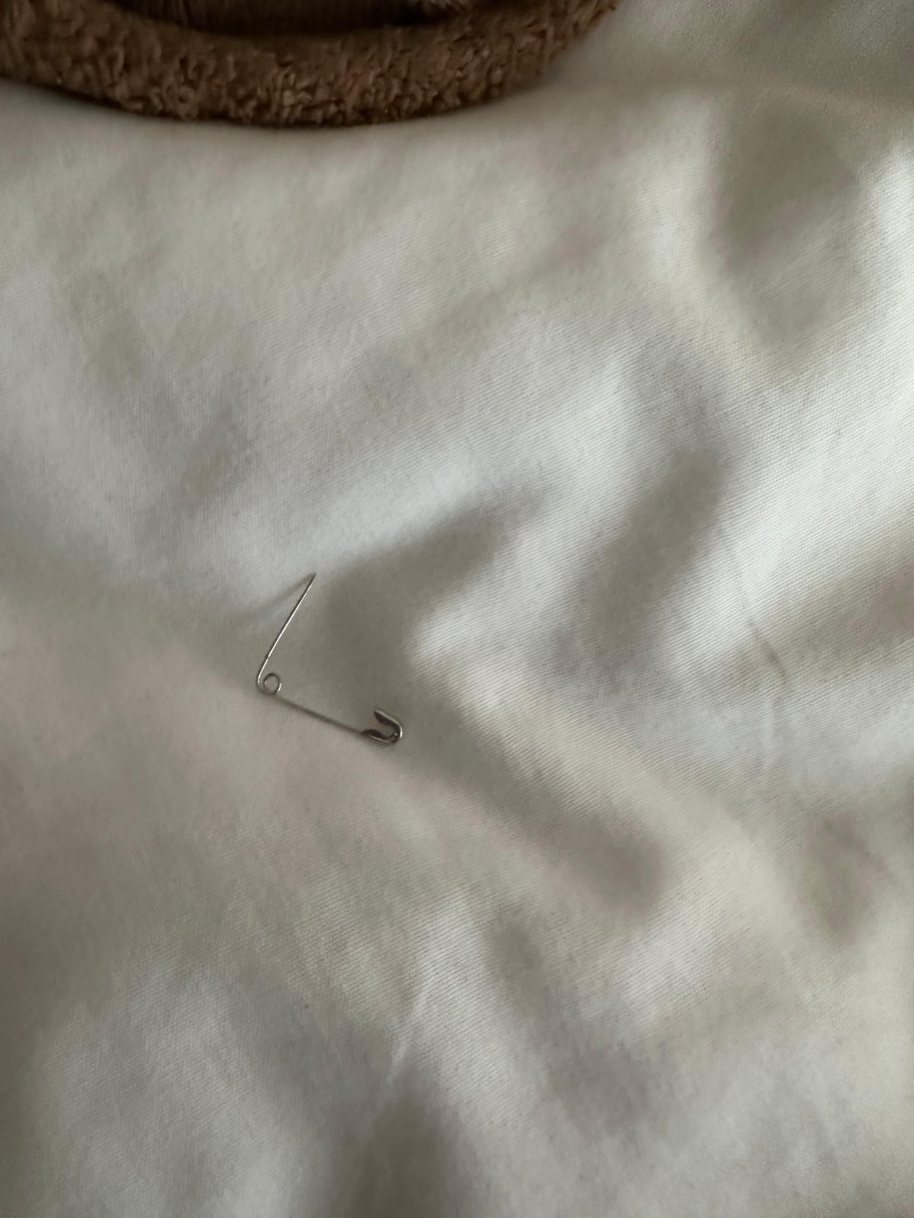 Move safety pin from brown blanket to sheet to take picture. Threw pin away in the trash