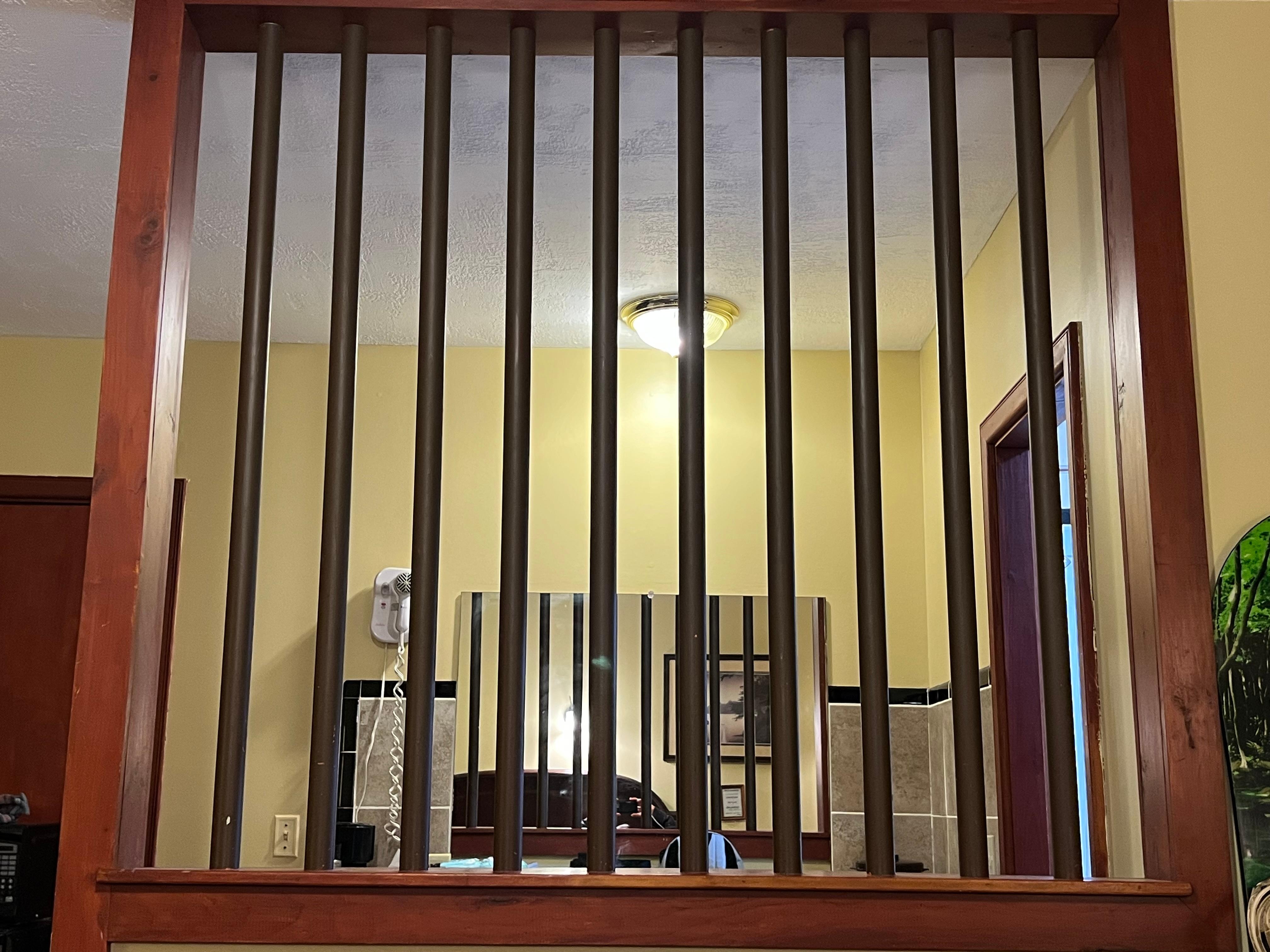 Metal bars separate the bathroom area from the bedroom.