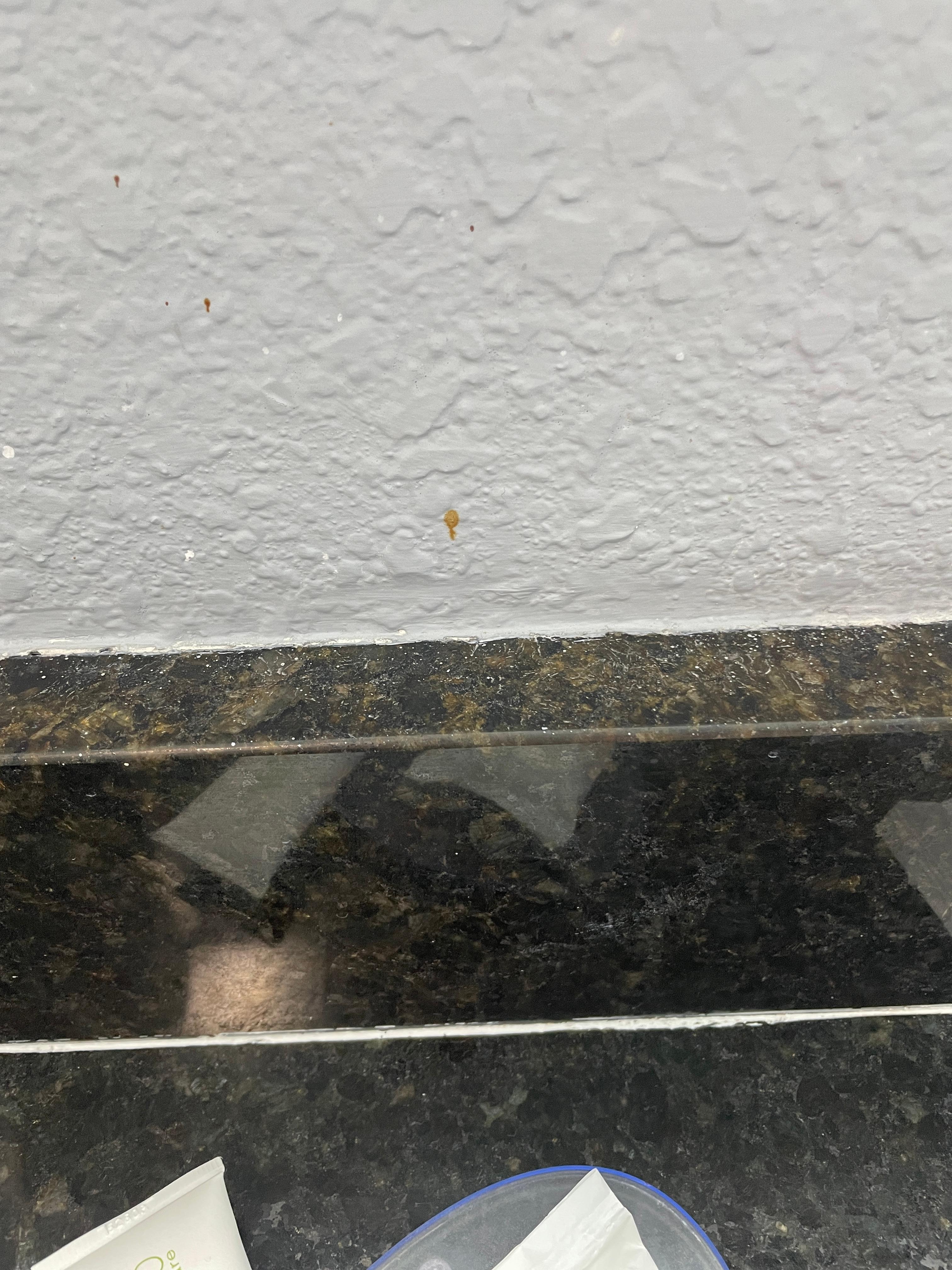 Brown splatter under mirror in bathroom