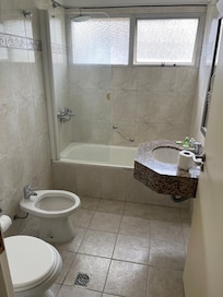 Banheiro velho. A água vaza pelo box e inunda a chão do banheiro