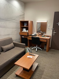 Bereich mit Sofa, Schreibtisch, Kaffeemaschine und Kühlschrank.