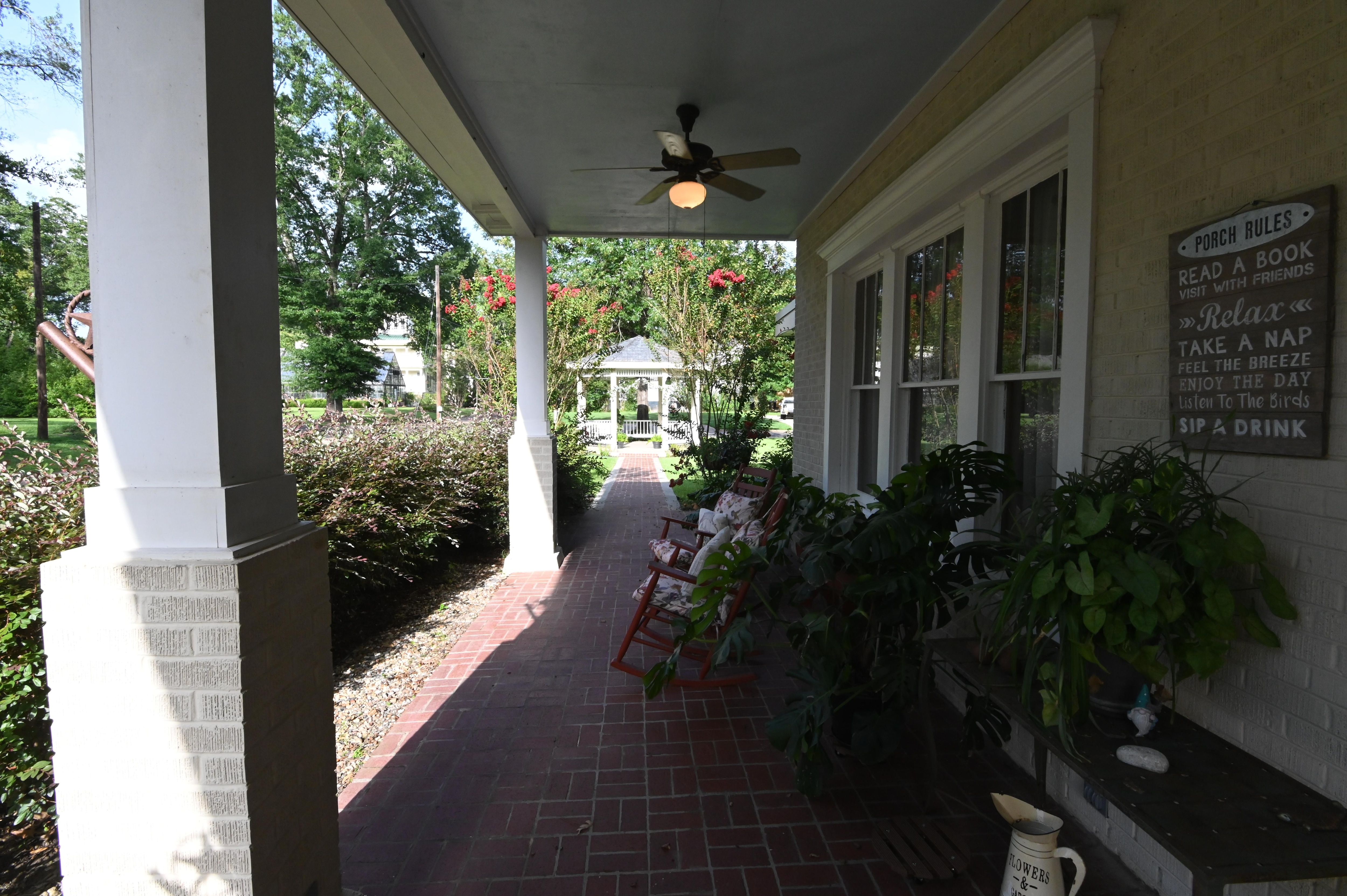 Such a gorgeous and inviting front porch surrounded by beautiful flowers.