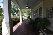 Such a gorgeous and inviting front porch surrounded by beautiful flowers.