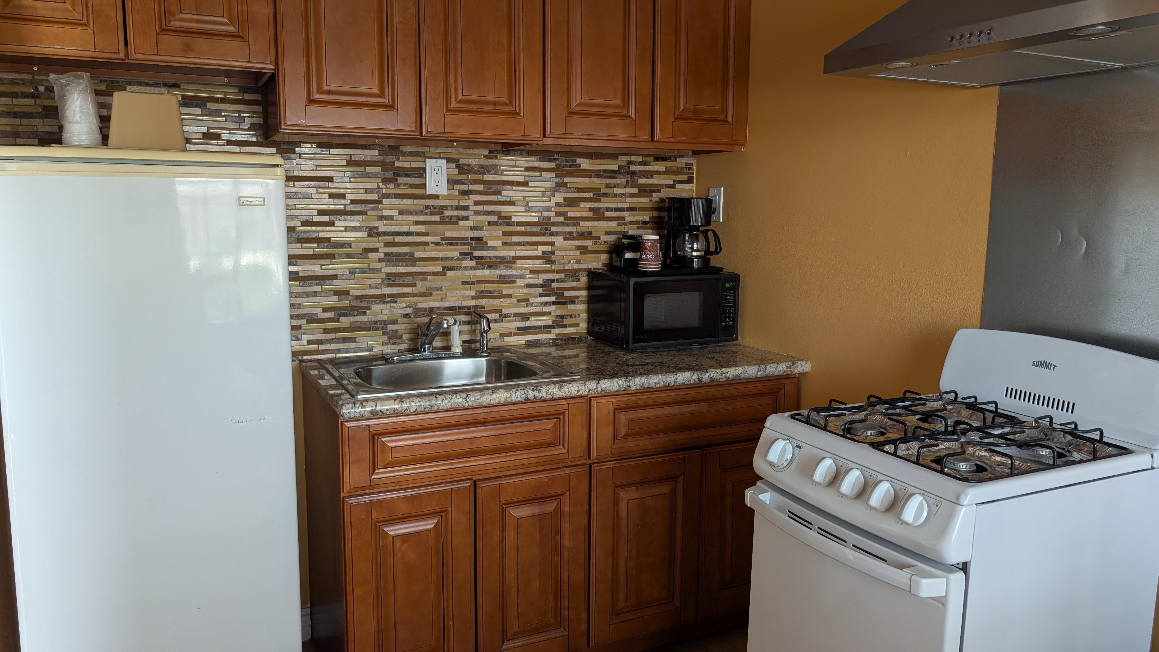 Small kitchenette with oven range, fridge and microwave