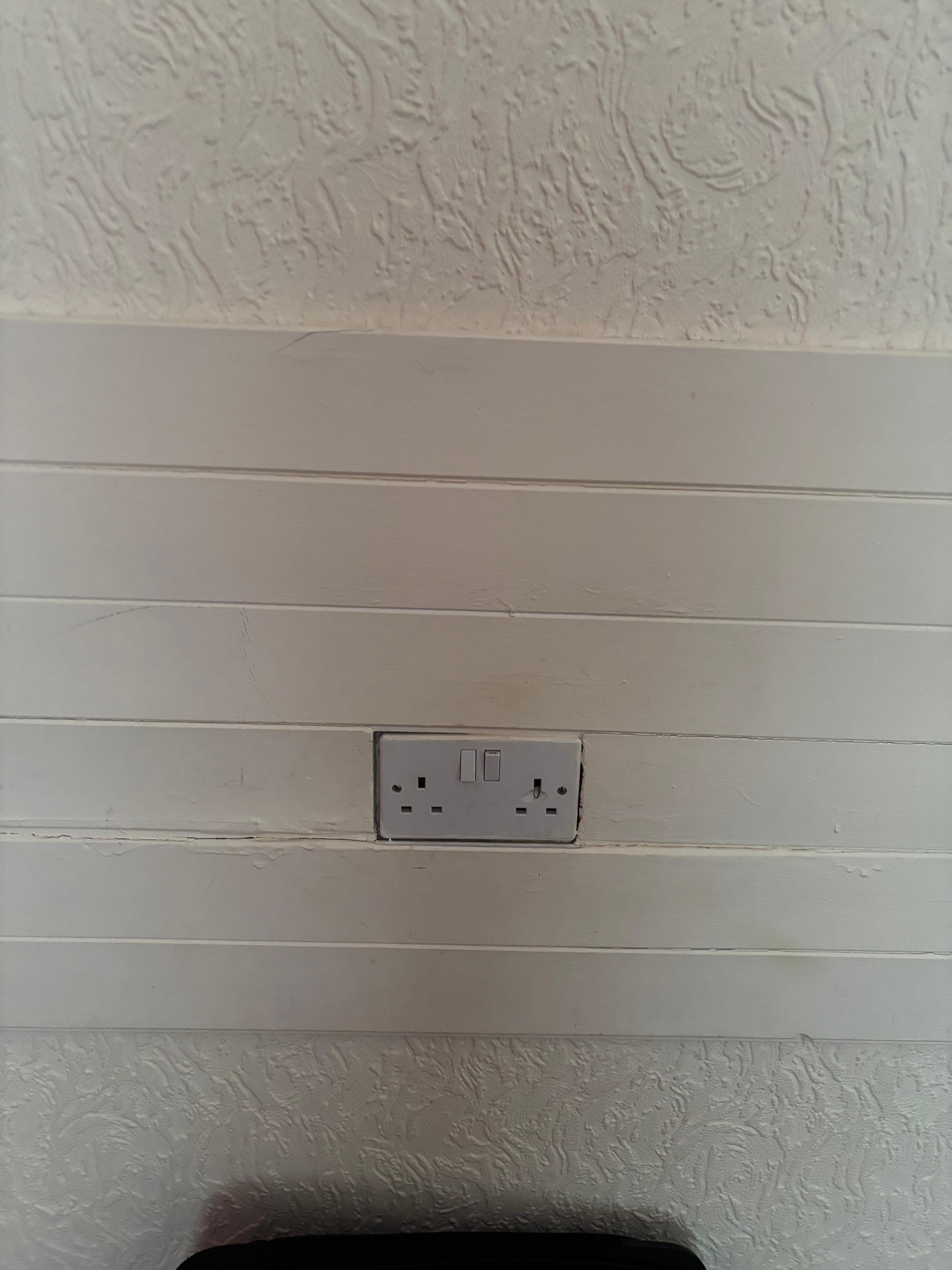 Unsafe electrical outlets set within a wooden panel