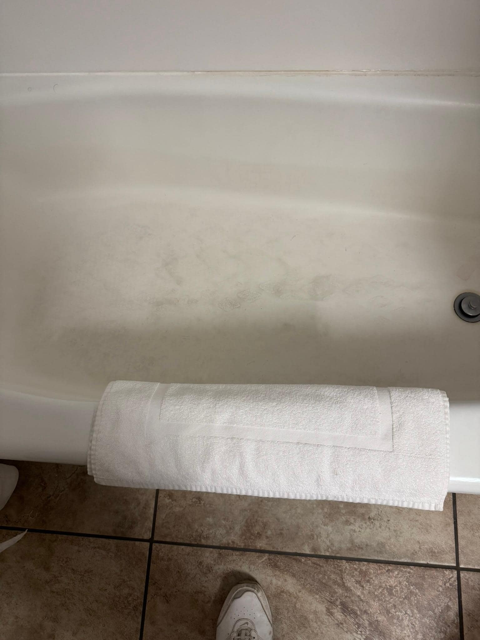 Actual bathroom condition showing bathtub surface staining and lack of expected cleanliness.