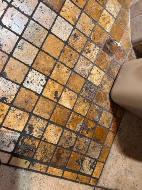 The bathroom floor is dirty and old.