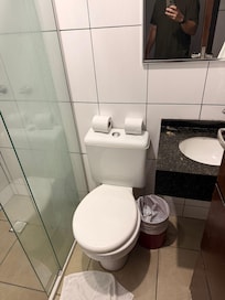 Banheiro sujo com o balde de lixo com “restos”