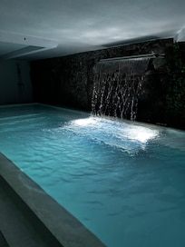 Piscine intérieure avec jacuzzi et chute d’eau