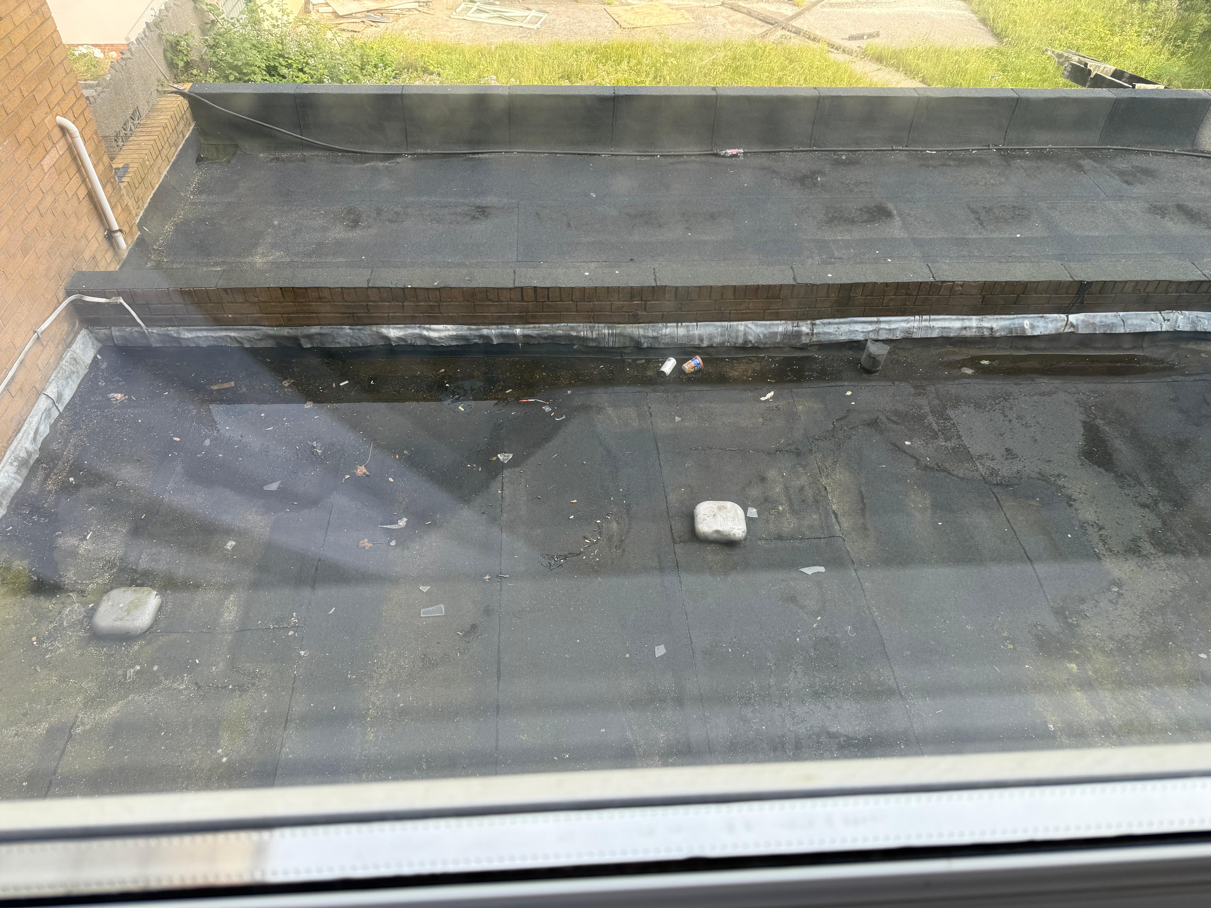 View of flat roof with litter and broken glass