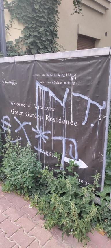 Defaced welcome sign: Graffiti-covered and surrounded by overgrown weeds, clearly showing neglect.